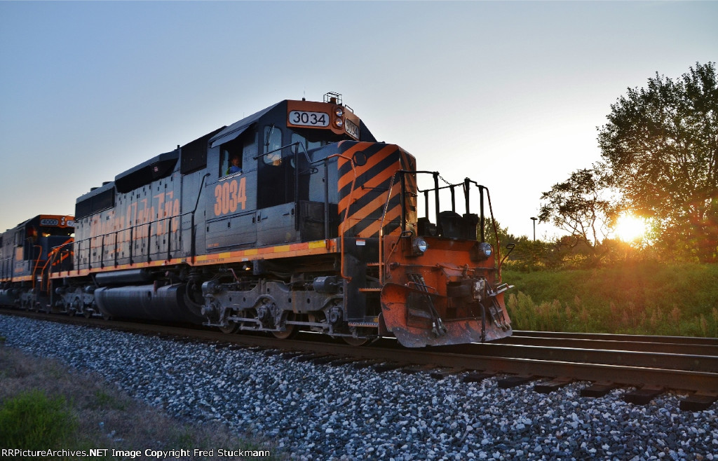 WE 3034 is waiting behind 2 other trains.